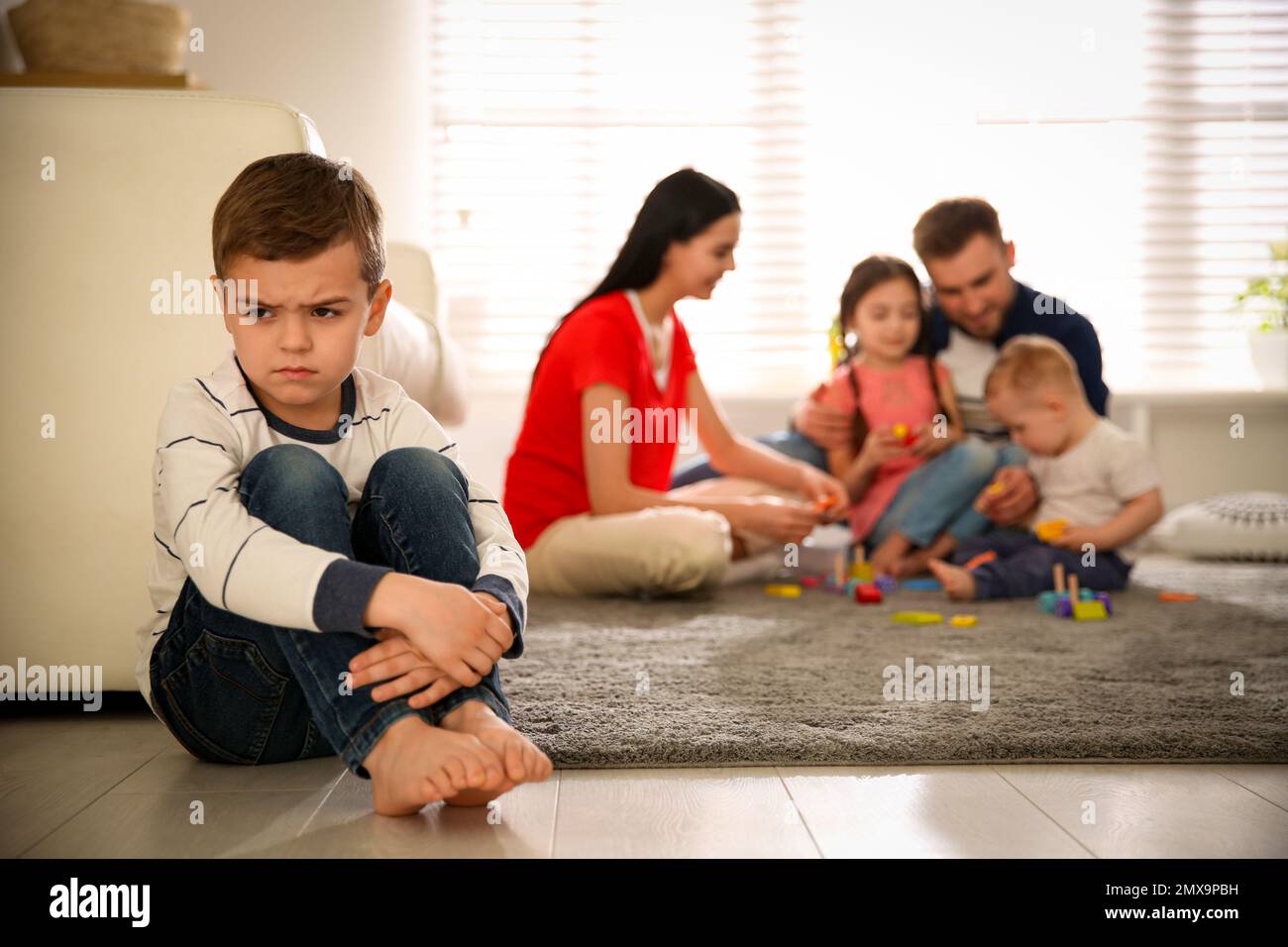 Unhappy little boy feeling jealous while parents spending time with ...