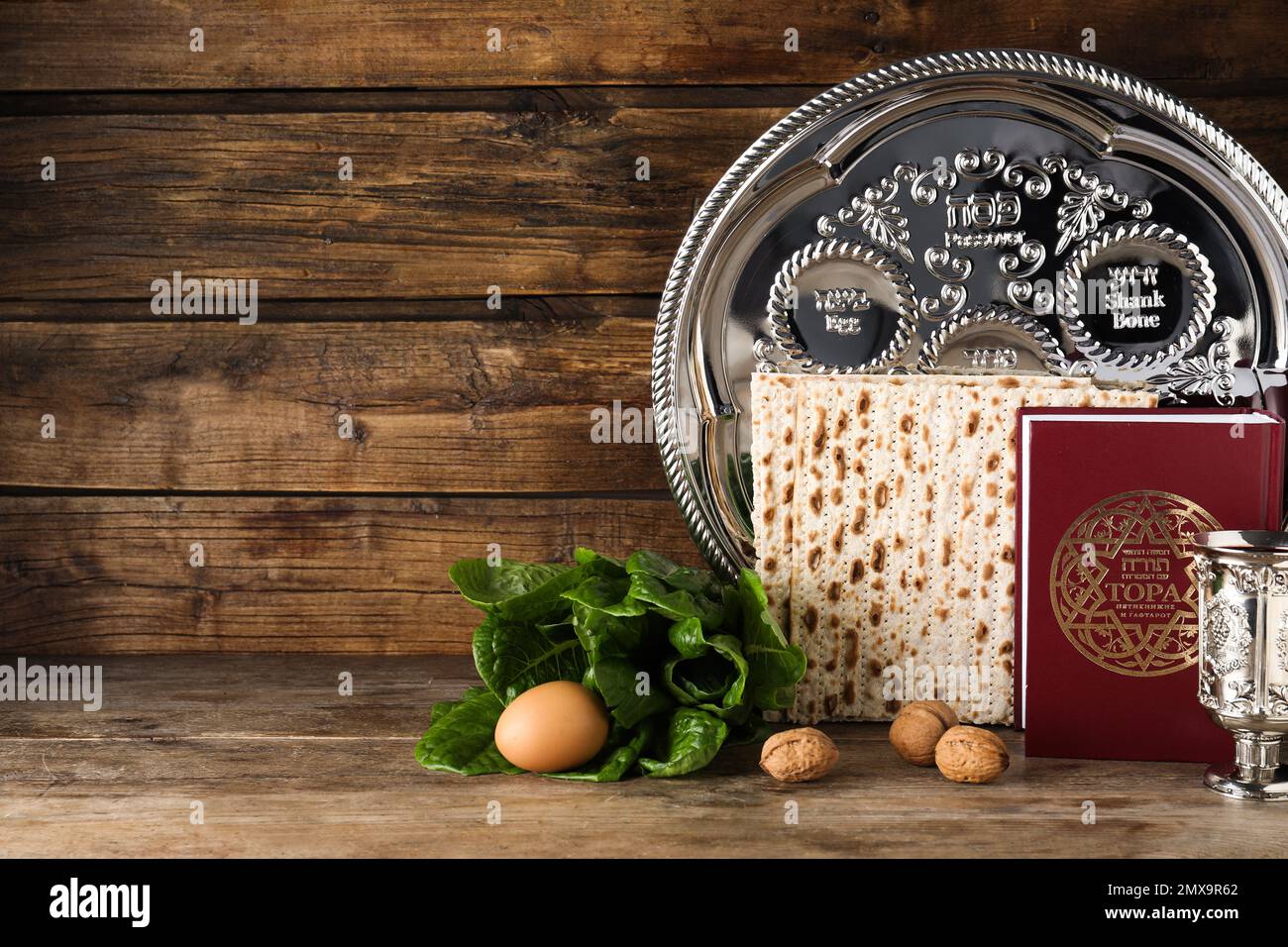 Symbolic Pesach (Passover Seder) items on wooden table, space for text ...