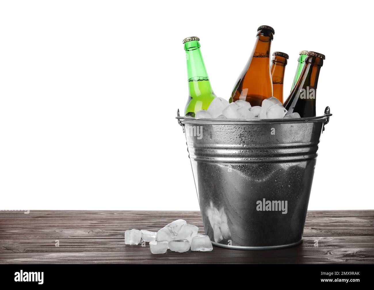 Metal bucket with bottles of beer and ice cubes on wooden table against ...
