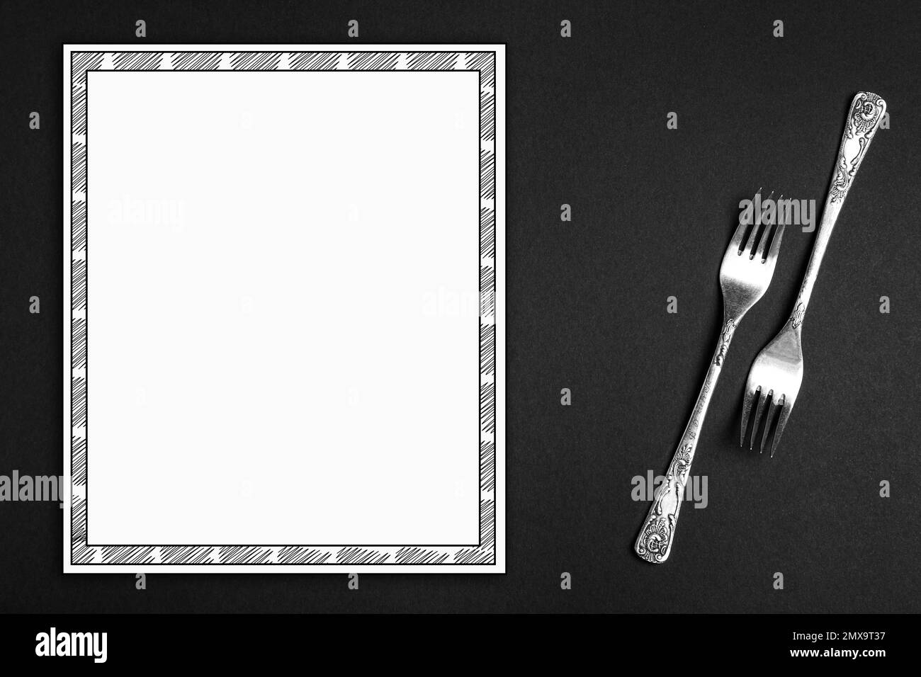 Silver forks and empty menu on black background, flat lay. Space for ...