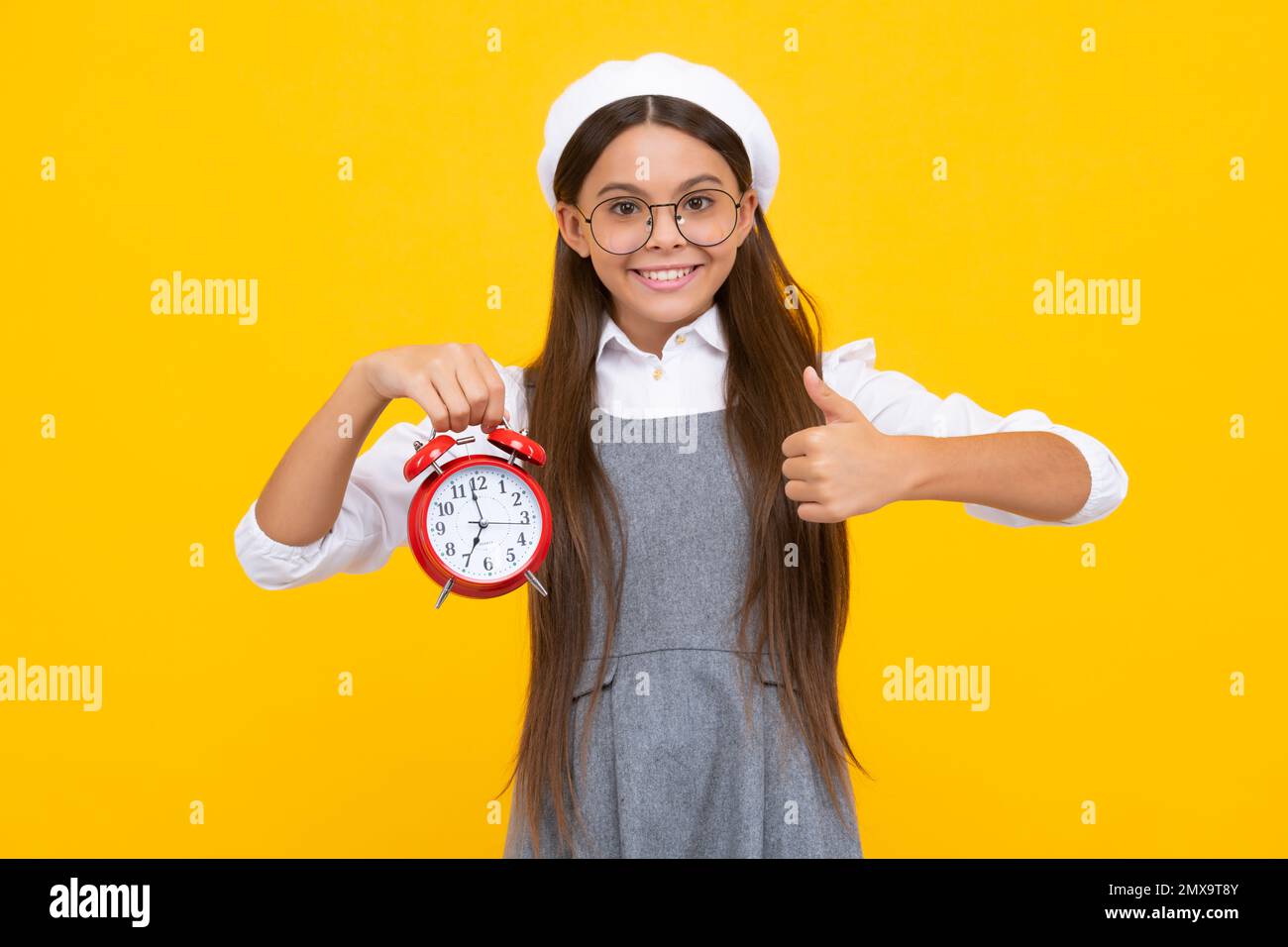 Teen student girl hold clock isolated on yellow background. Time to ...