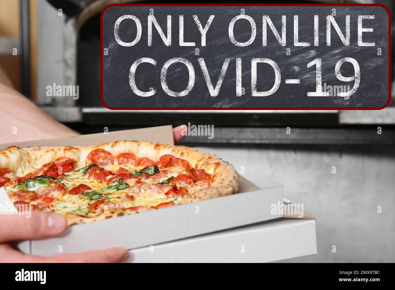 Chef holding delivery box with oven baked pizza in restaurant, closeup ...