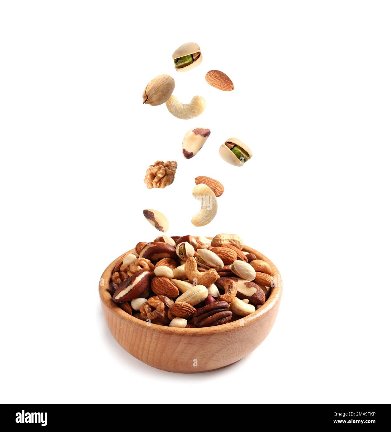 Different nuts falling into bowl on white background Stock Photo - Alamy