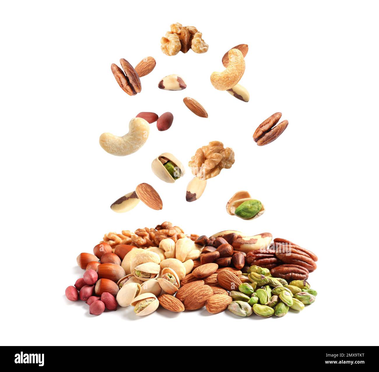 Different nuts falling into pile on white background Stock Photo - Alamy