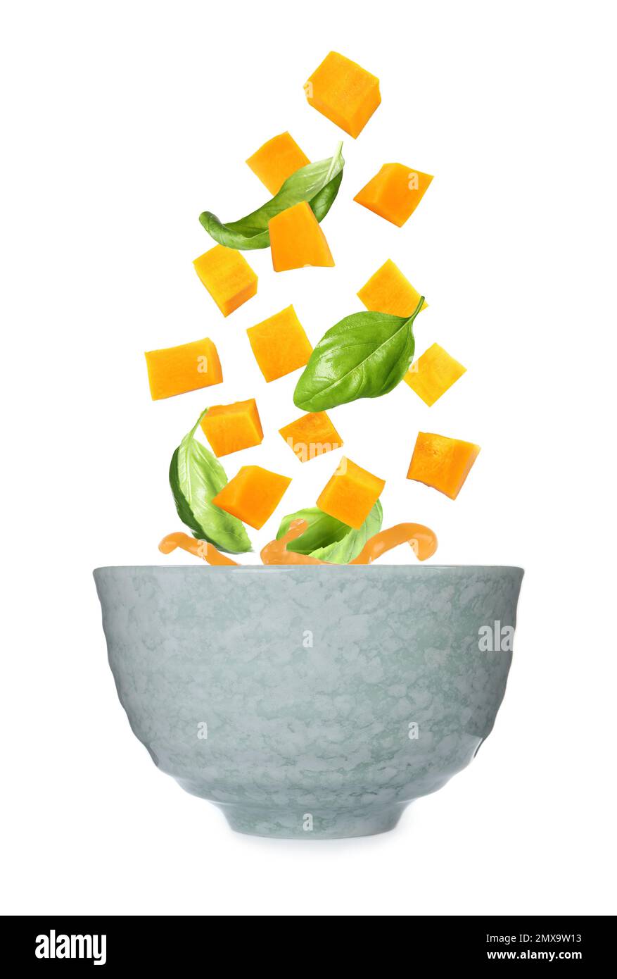 Ingredients falling into bowl of homemade pumpkin soup on white ...