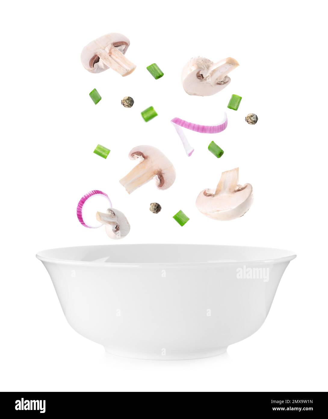 Fresh mushrooms and other ingredients falling into bowl on white ...