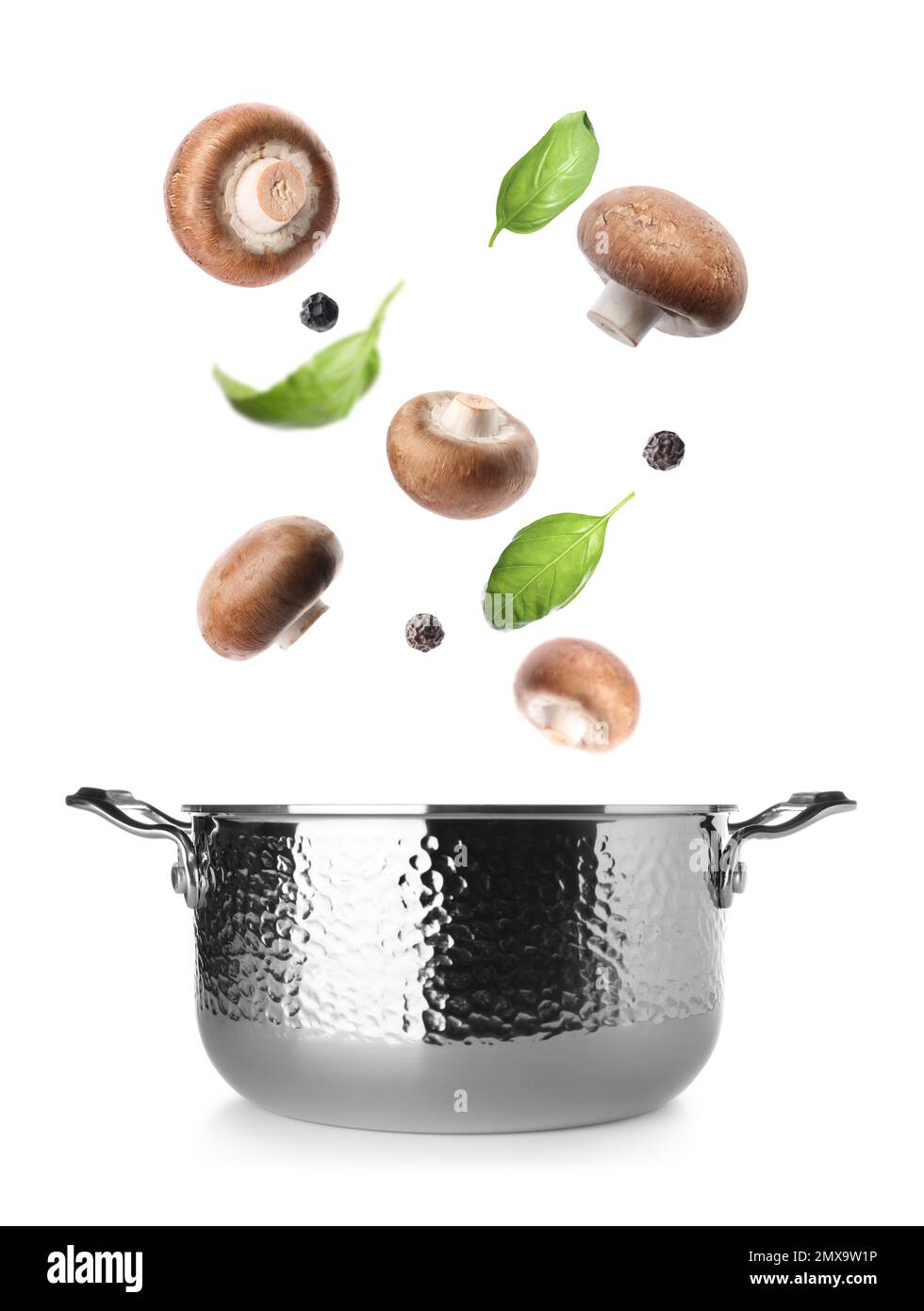 Fresh mushrooms, basil and peppercorns falling into pot on white ...