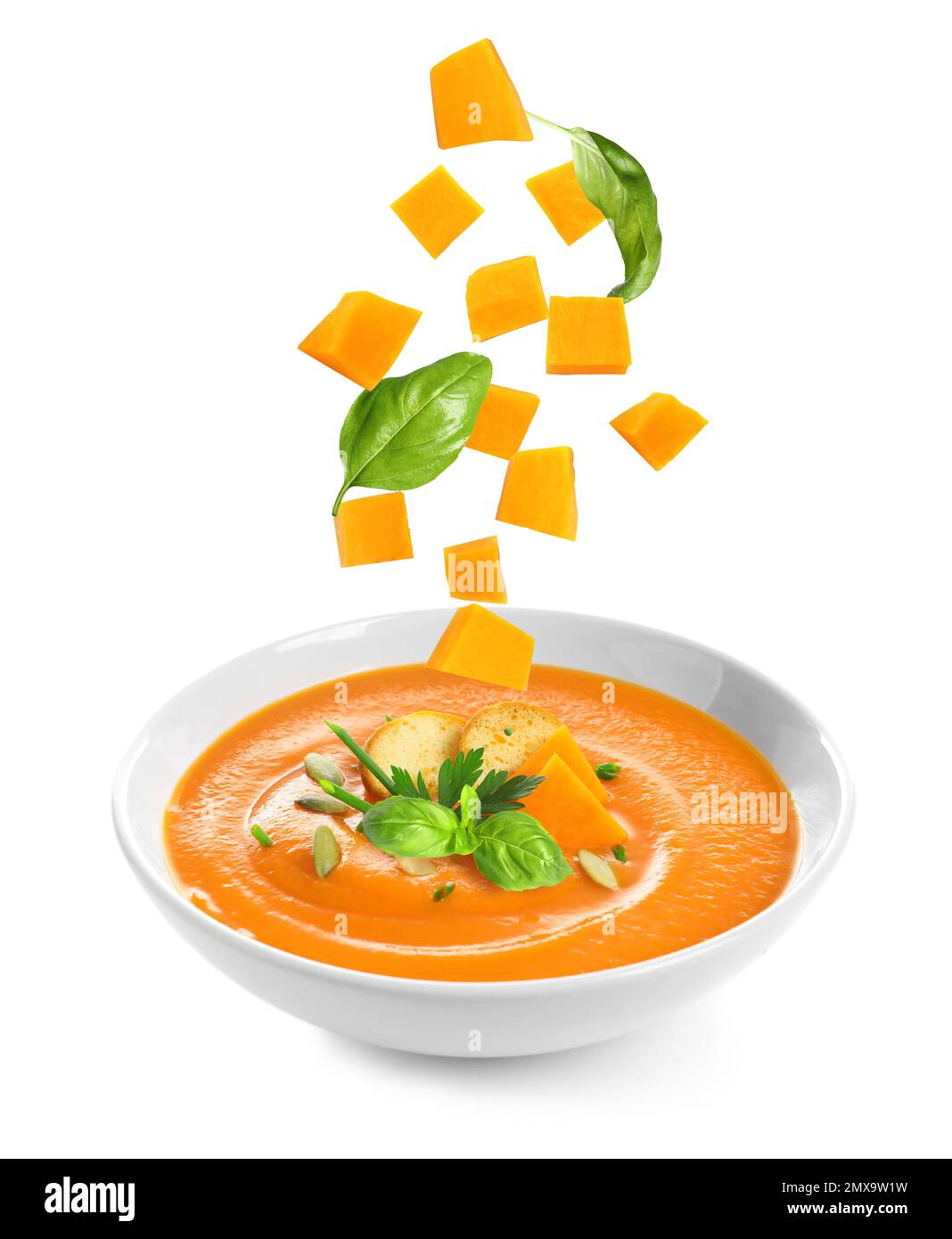 Ingredients falling into bowl of homemade pumpkin soup on white ...
