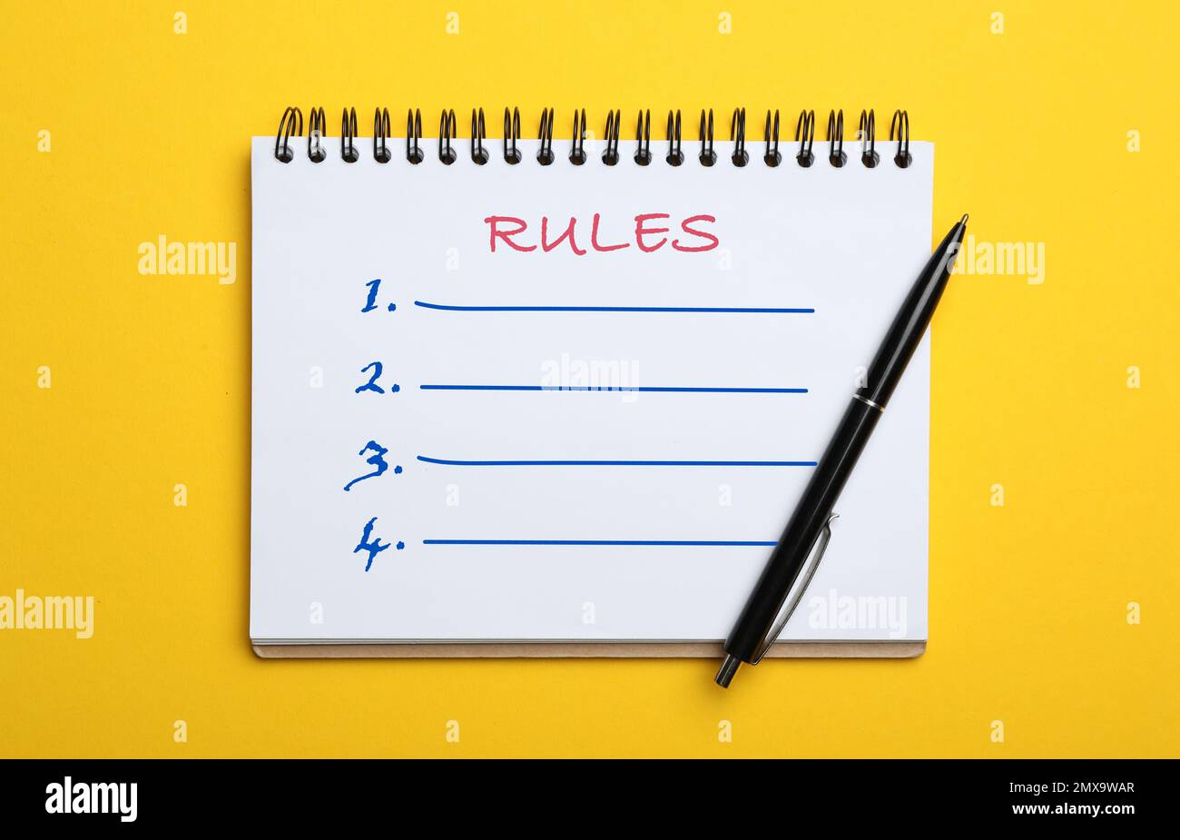 Notebook with list of rules and pen on yellow background, top view ...