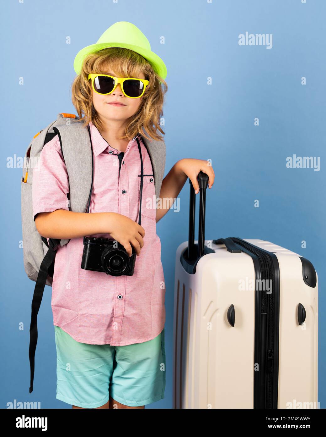 Child traveler with suitcase isolated on studio background. Tourist kid ...