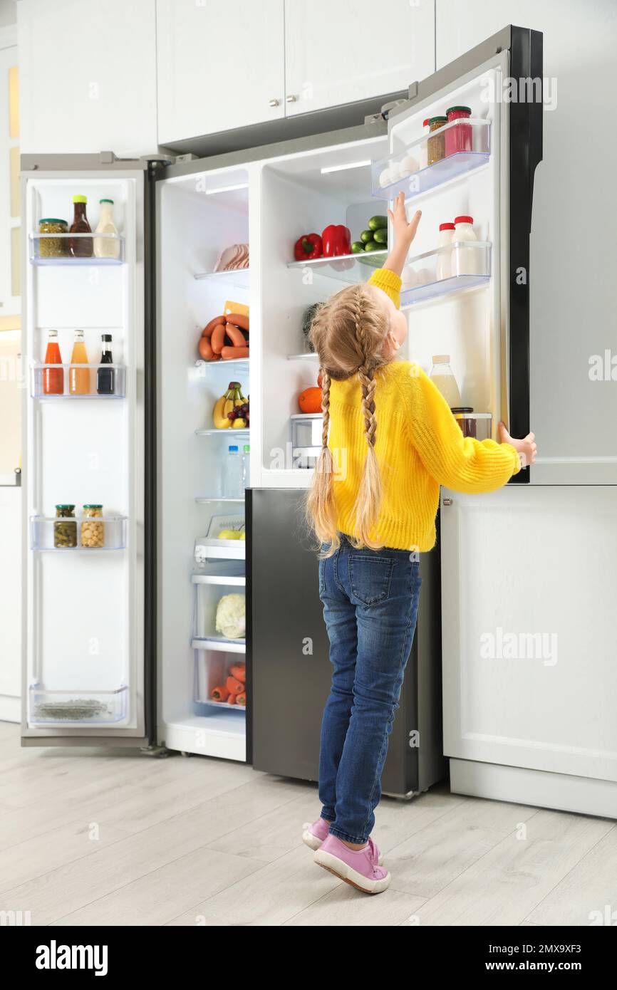 Little girl near open refrigerator in kitchen Stock Photo - Alamy