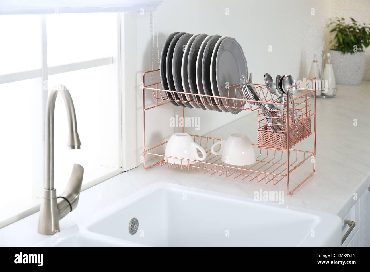Clean dishes on drying rack in modern kitchen interior Stock Photo - Alamy