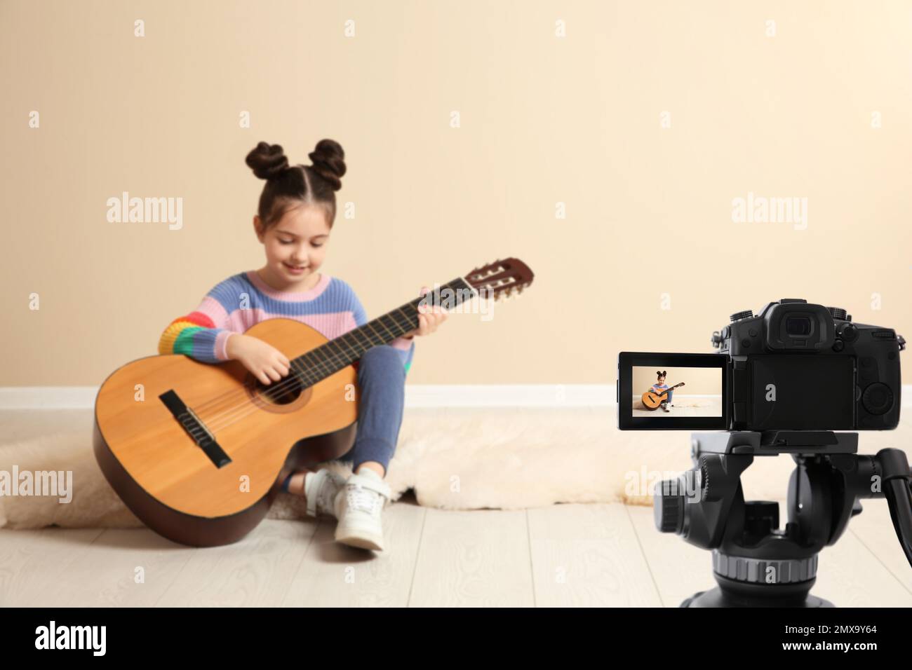 Little music teacher recording guitar lesson indoors Stock Photo - Alamy