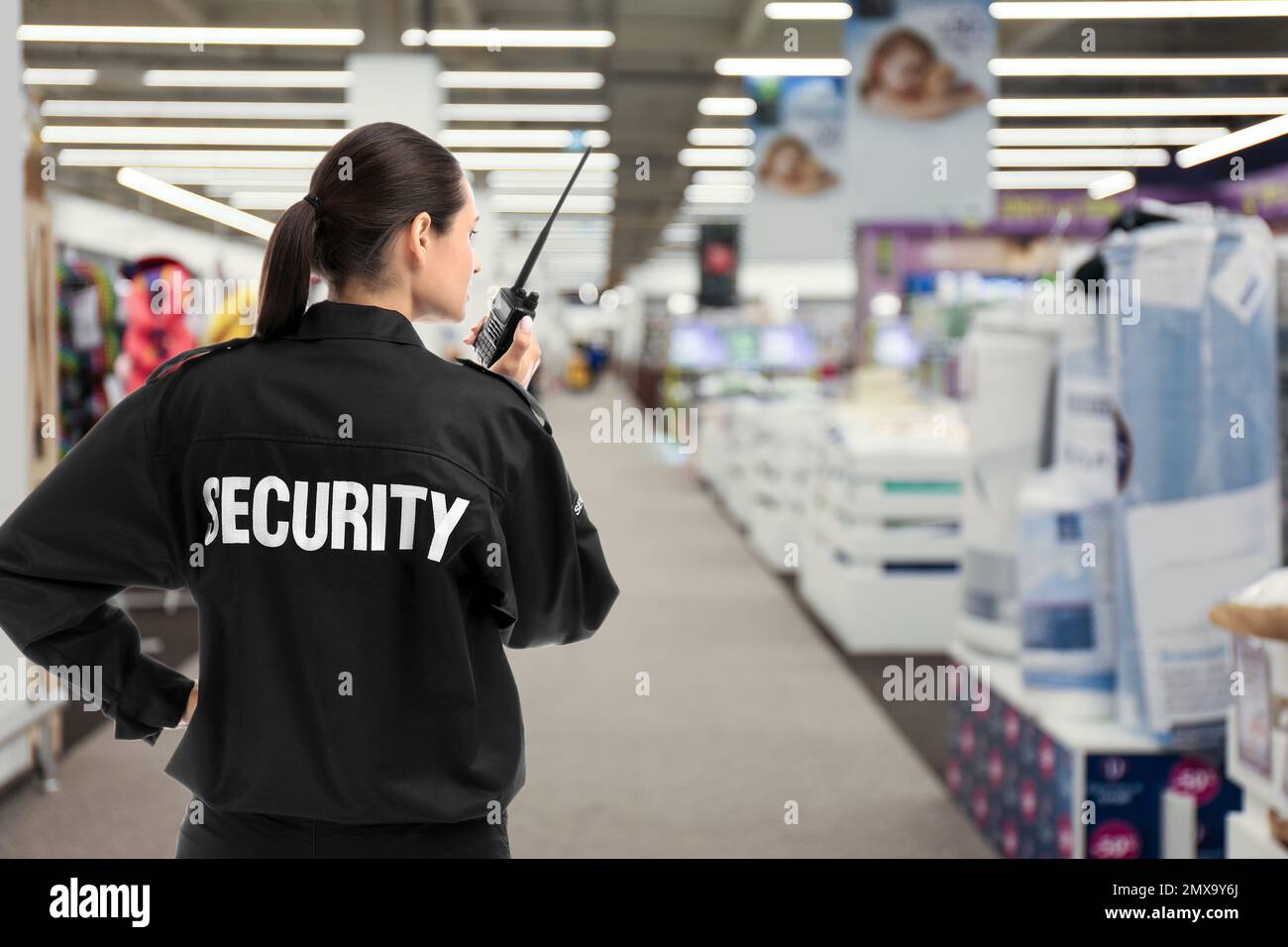 Security guard using portable radio transmitter in shopping mall, space ...
