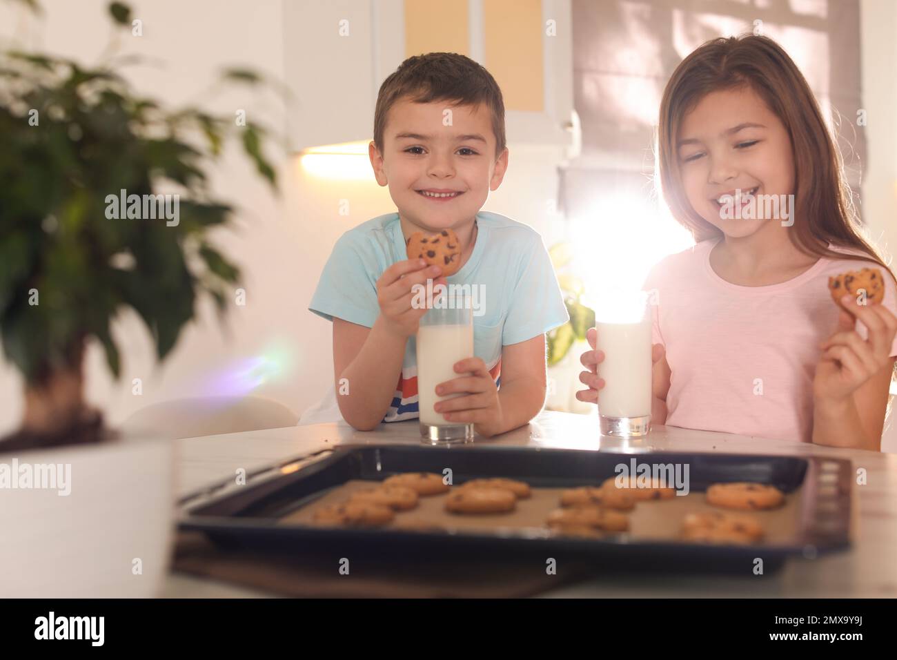 Cute little children eating cookies with milk in kitchen. Cooking ...