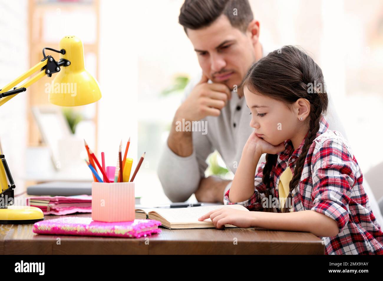 Man helping his daughter with homework at table indoors Stock Photo - Alamy