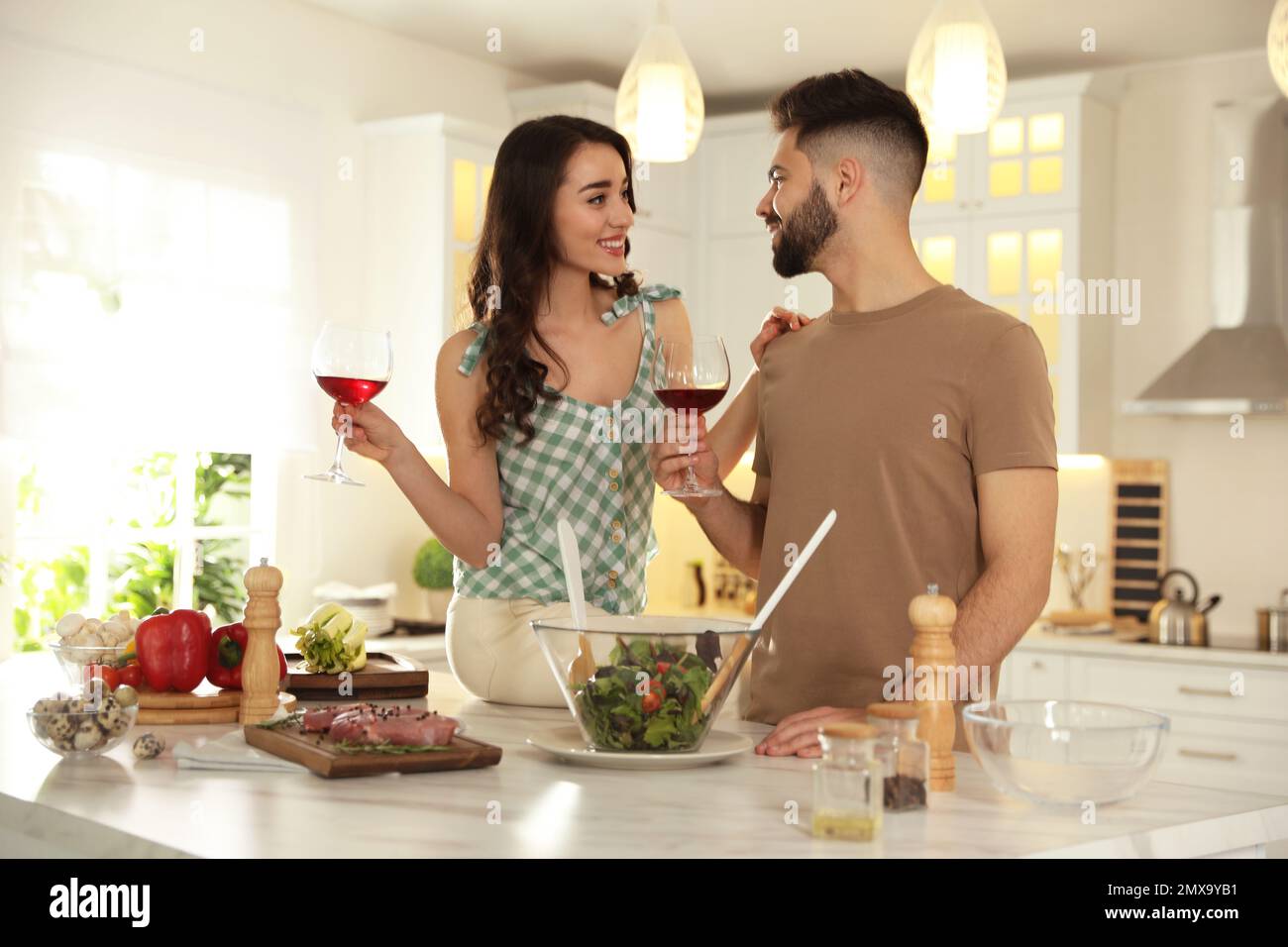 Lovely young couple drinking wine while cooking together at kitchen ...