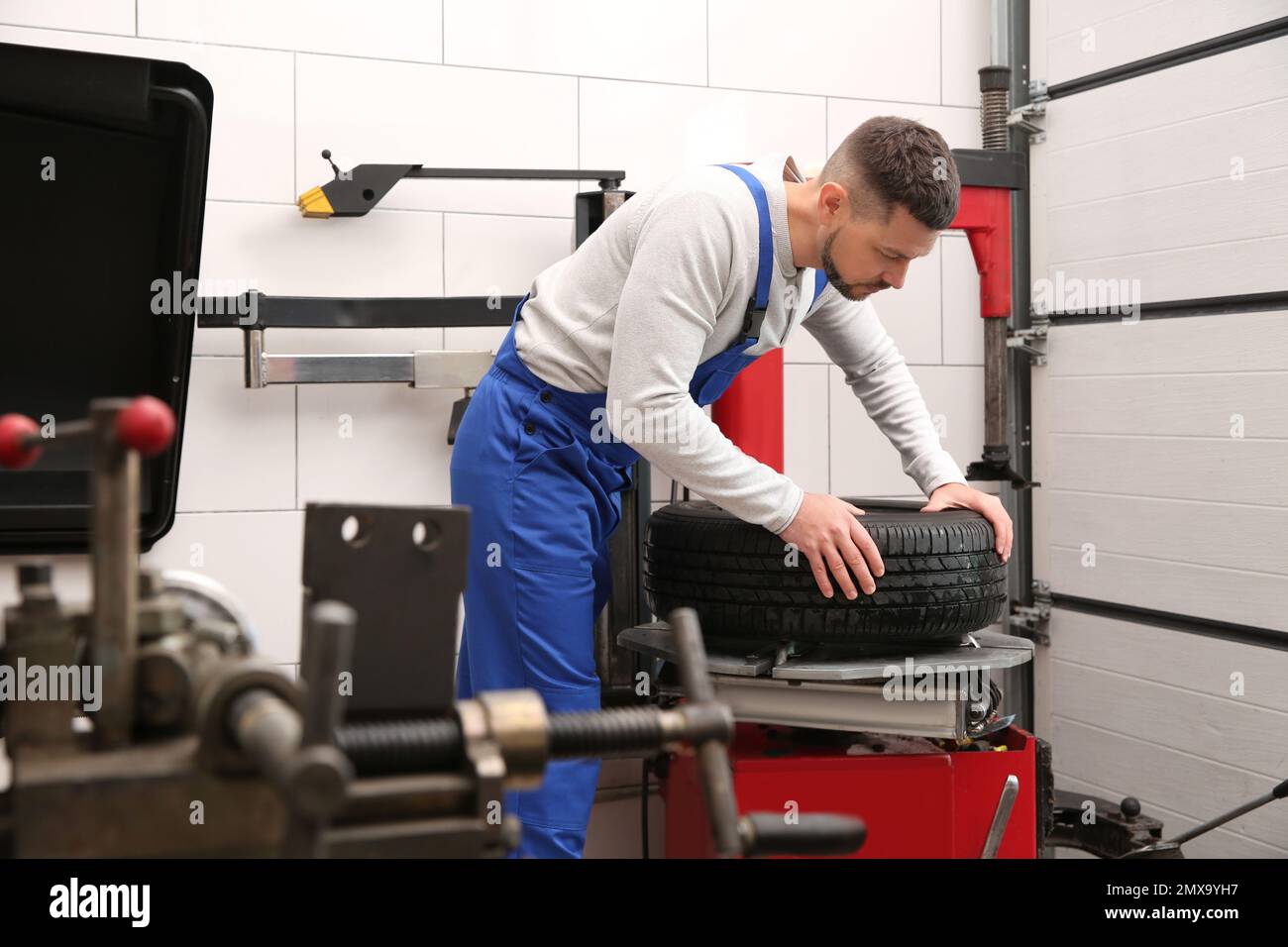 Mechanic working with tire fitting machine at car service Stock Photo ...