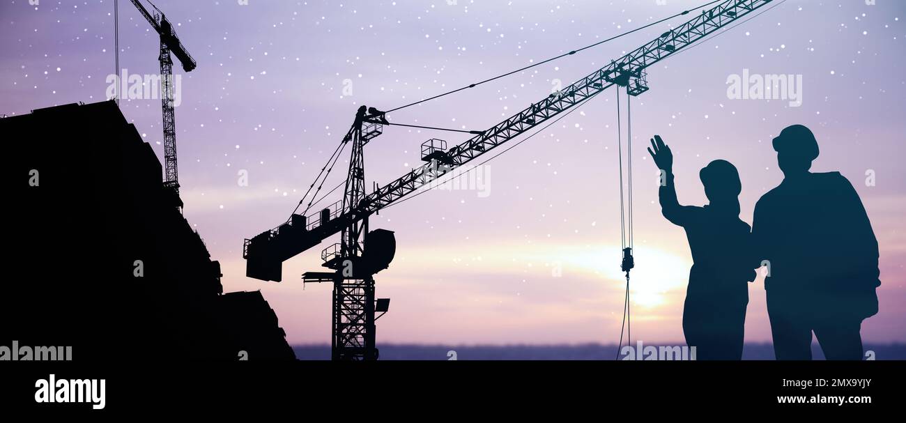 Silhouettes of engineers near construction site at sunset. Banner ...