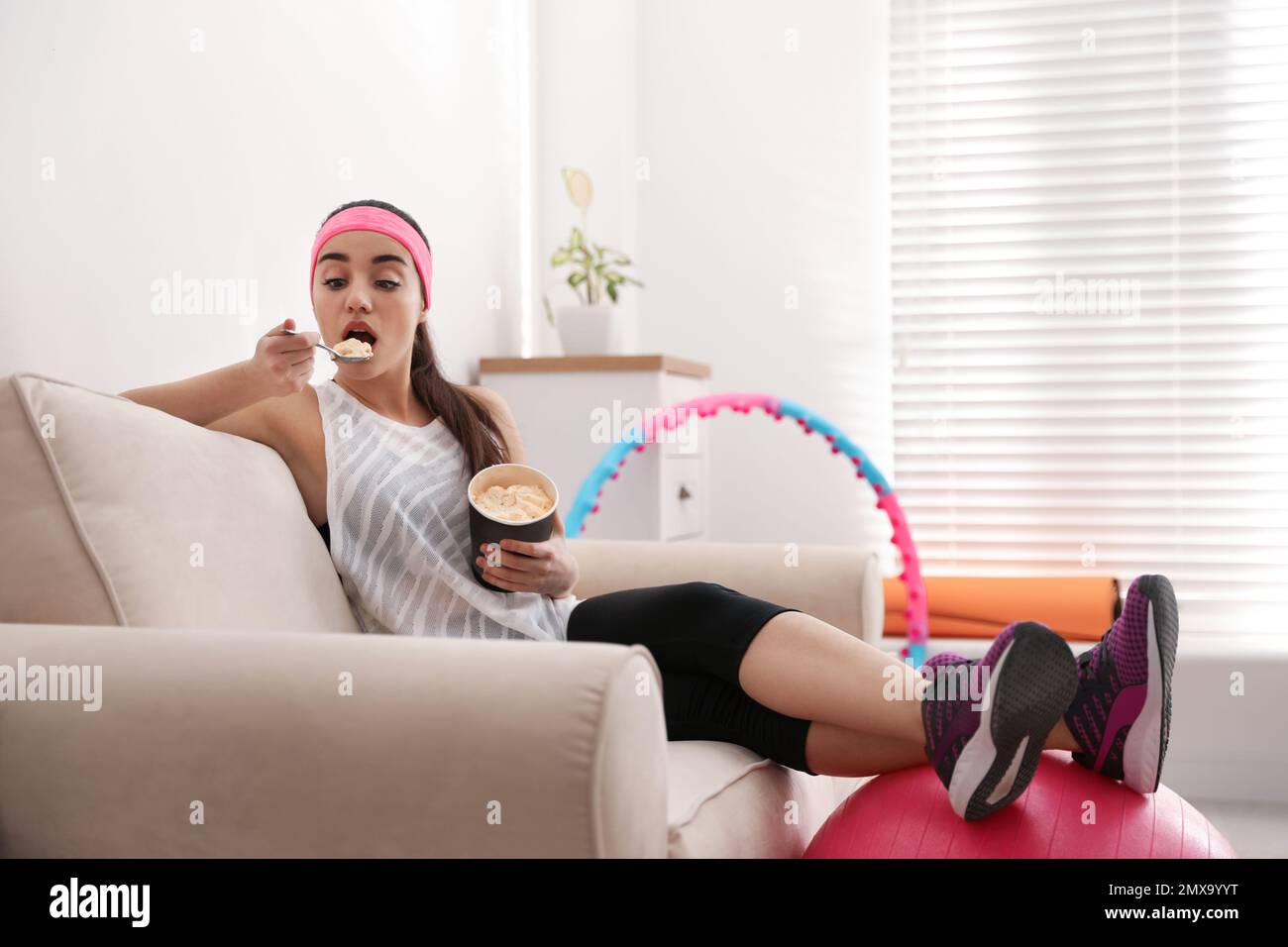 Lazy young woman eating ice cream instead of training at home Stock ...