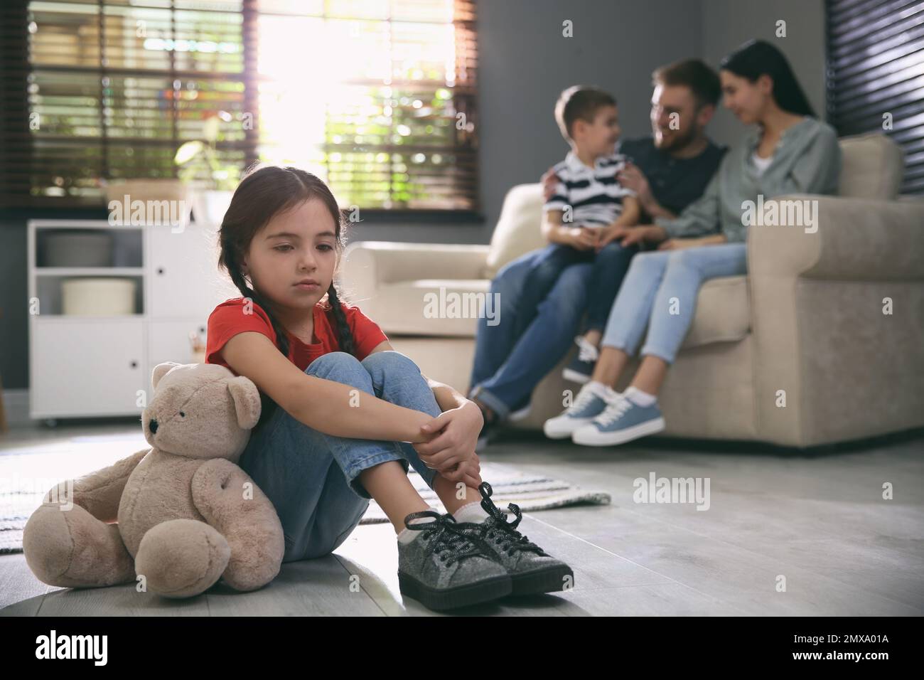 Unhappy little girl feeling jealous while parents spending time with ...