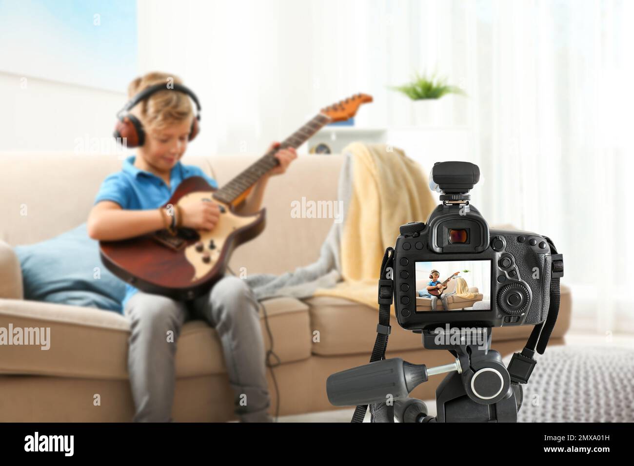 Little music teacher recording guitar lesson indoors Stock Photo - Alamy