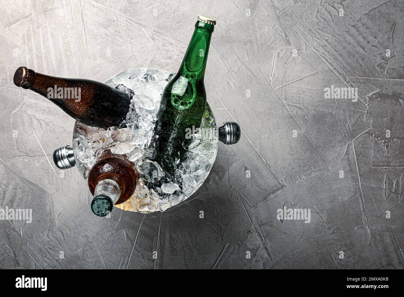 Beer in metal bucket with ice on grey table, top view. Space for text ...