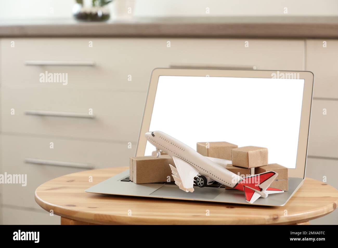 Laptop and plane model with boxes on table indoors. Courier service ...