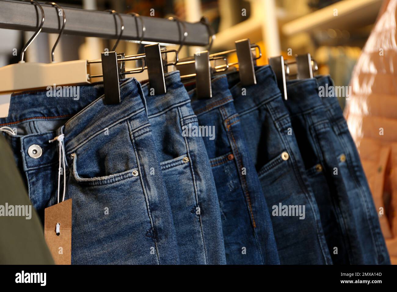 Modern jeans hanging on clothing rack in shop, closeup Stock Photo - Alamy