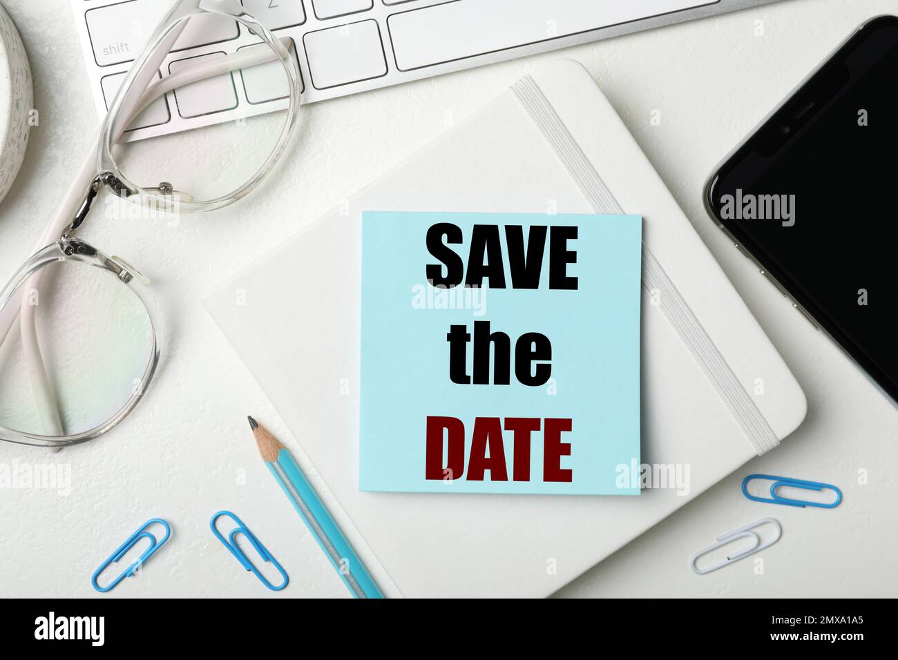 Notebook, eyeglasses and sheet of paper with phrase SAVE THE DATE on ...