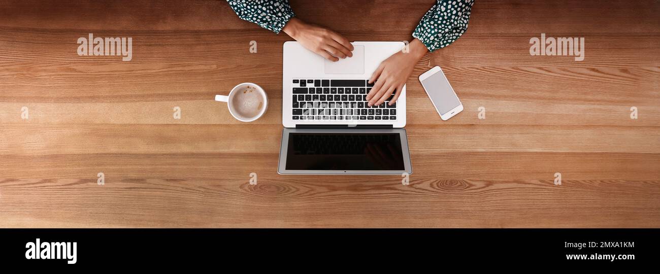 Young woman working on computer at table indoors, top view. Banner ...