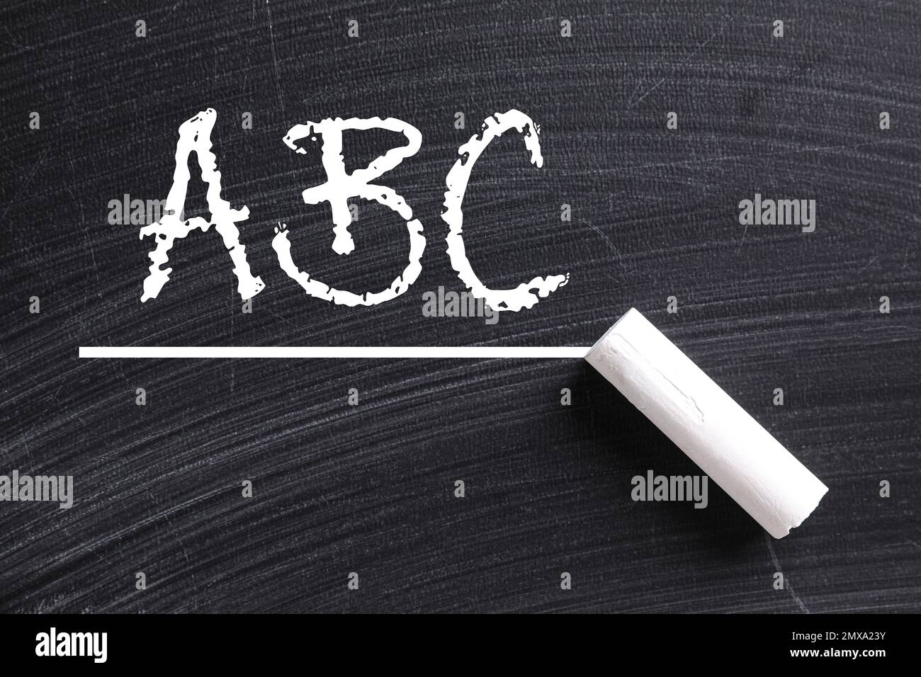 Piece of white chalk and letters ABC written on blackboard, top view ...