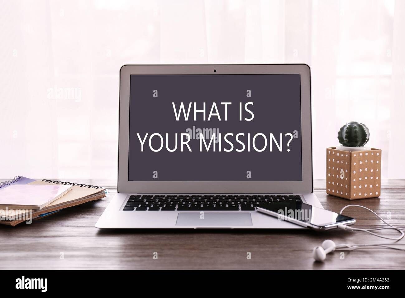 Modern laptop with question WHAT IS YOUR MISSION? on screen indoors ...