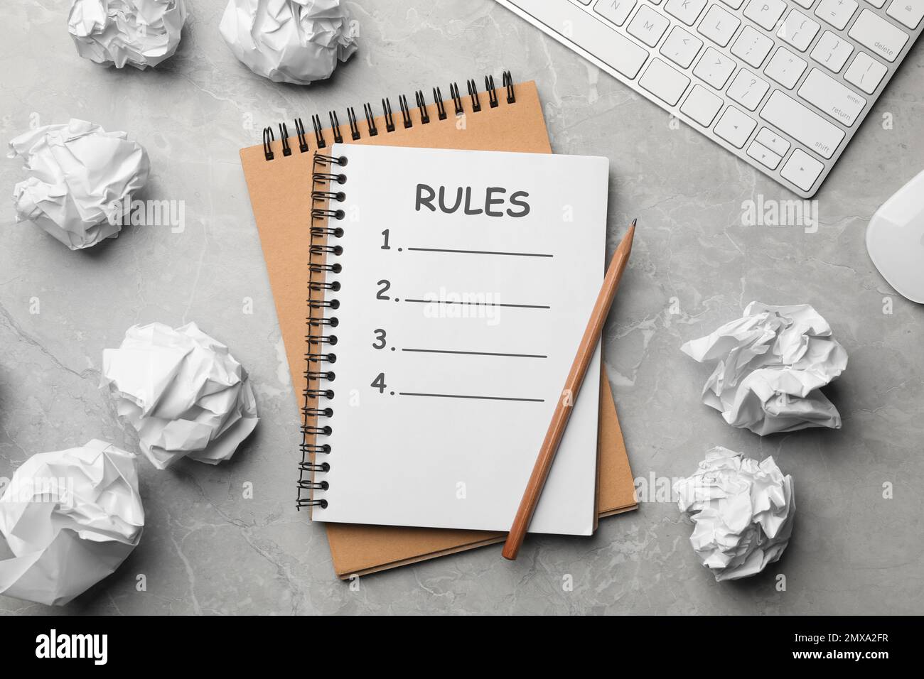 Notebook with list of rules and crumpled paper balls on grey marble ...