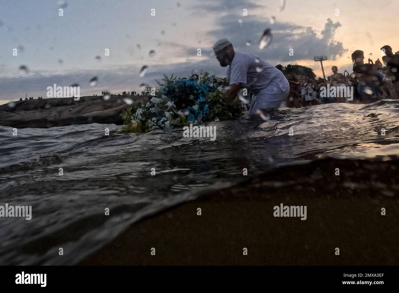 A devotee of the sea goddess Yemanja places flowers offerings for her ...