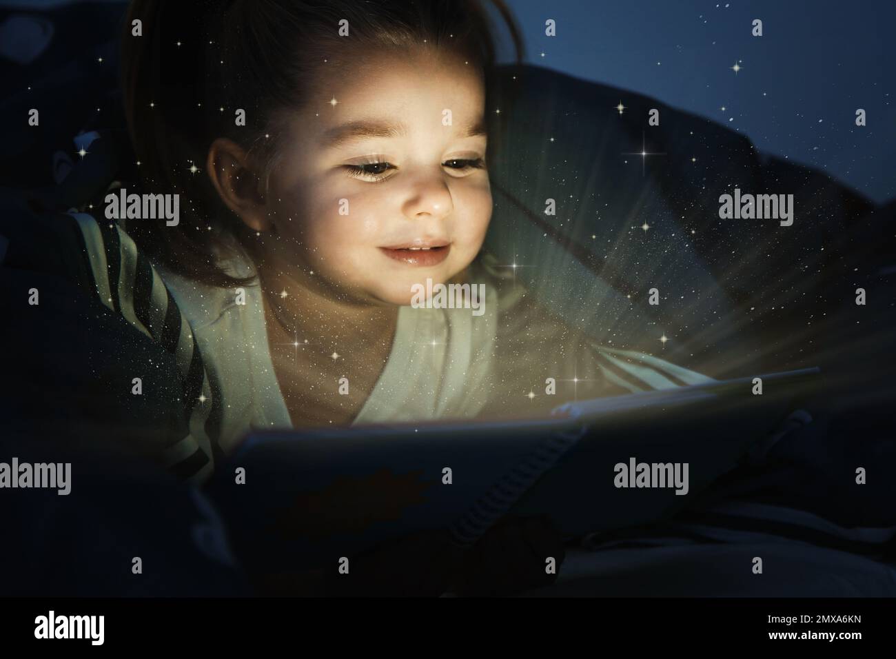 Cute little child reading magic book in darkness Stock Photo - Alamy