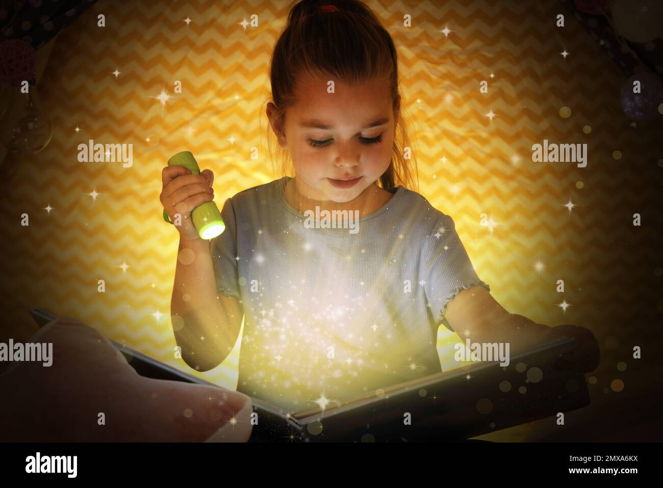 Cute little child reading magic book in play tent Stock Photo - Alamy