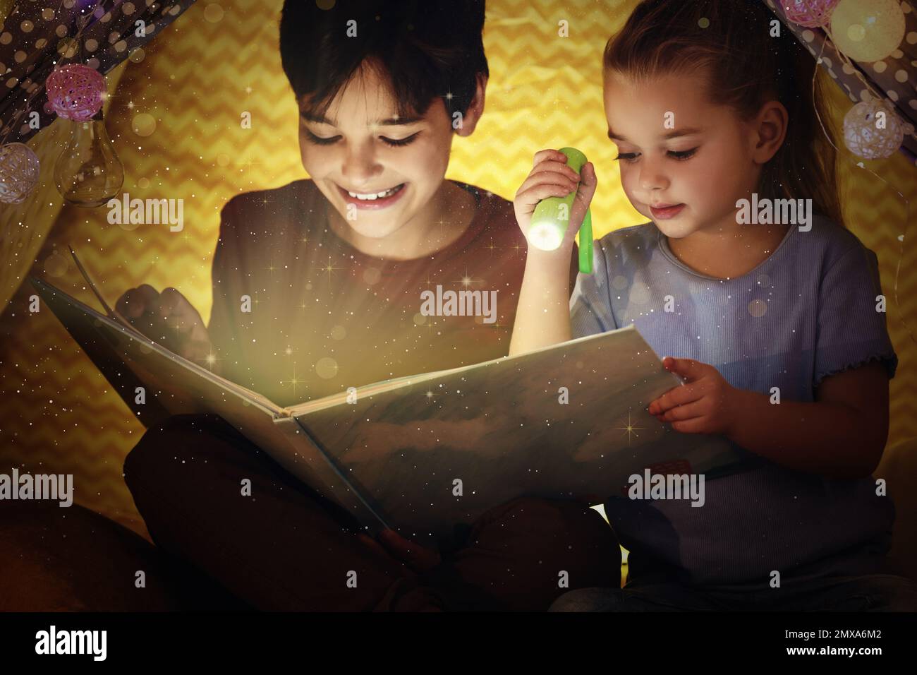 Cute little children reading magic book in play tent Stock Photo - Alamy
