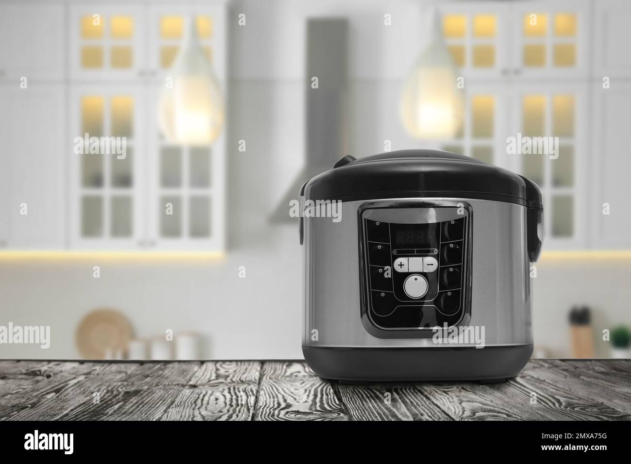 Modern electric multi cooker on wooden table in kitchen. Space for ...