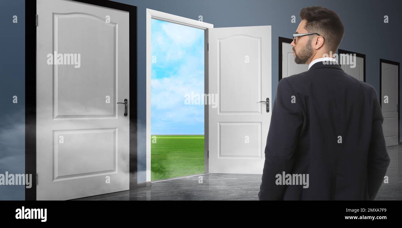 Young man standing in front of many doors. Choice concept Stock Photo ...