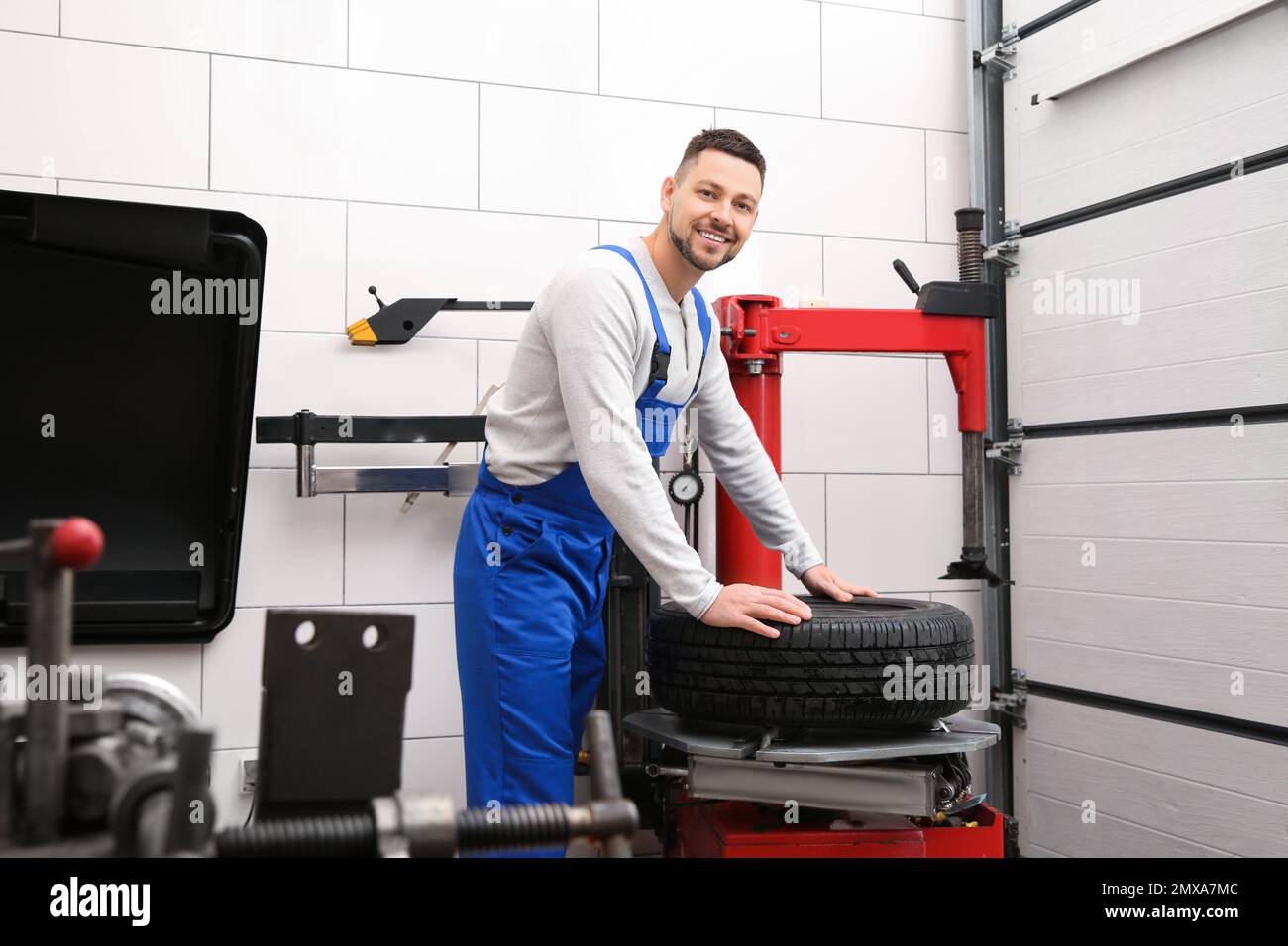 Mechanic working with tire fitting machine at car service Stock Photo ...