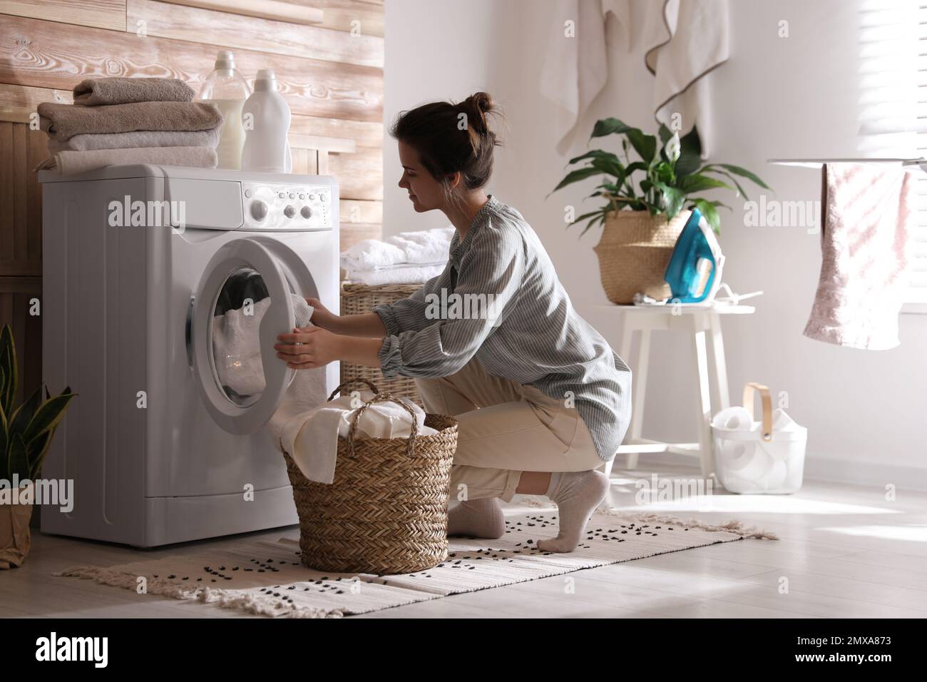 Young woman taking laundry out of washing machine at home Stock Photo - Alamy
