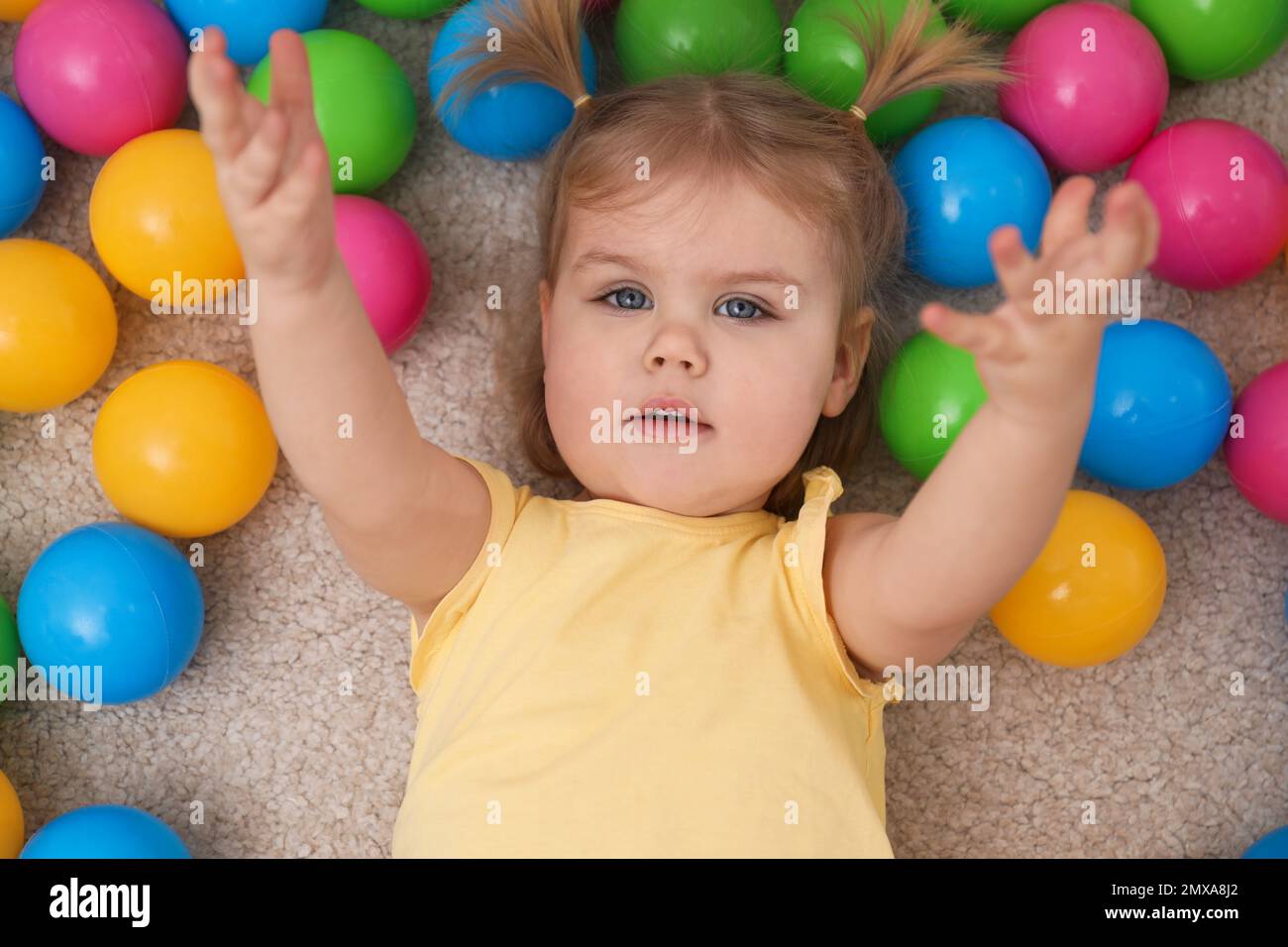 Cute little child playing with balls on floor, top view Stock Photo - Alamy
