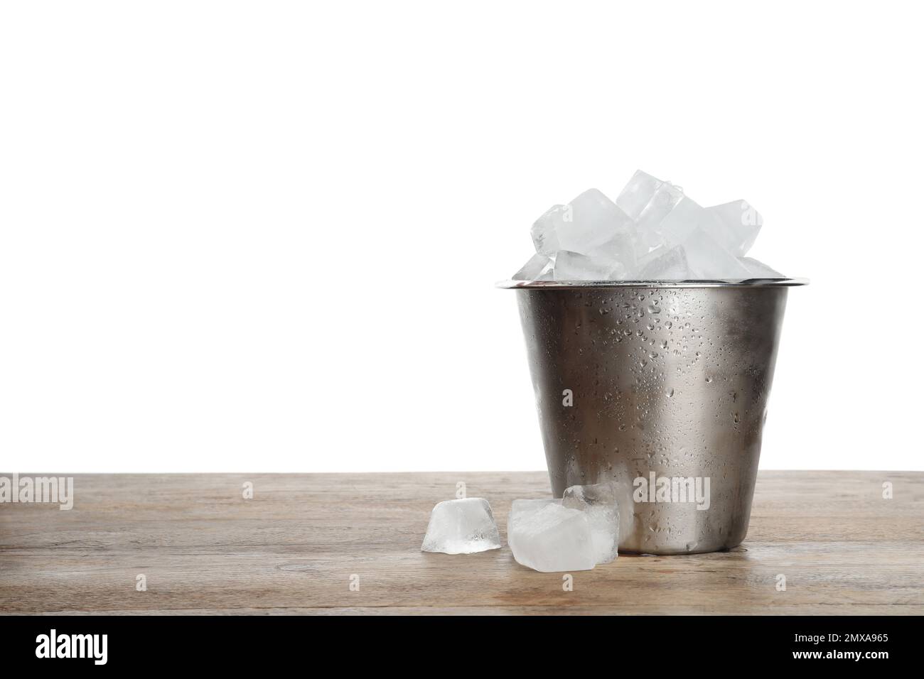 Metal bucket with ice cubes on wooden table against white background ...