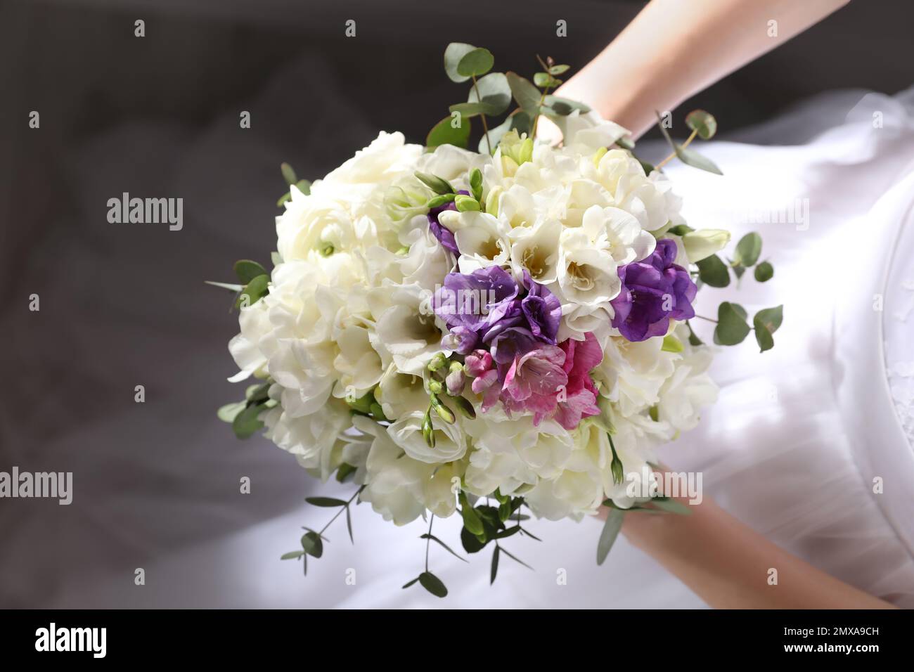 Bride holding beautiful bouquet with spring freesia flowers, closeup ...