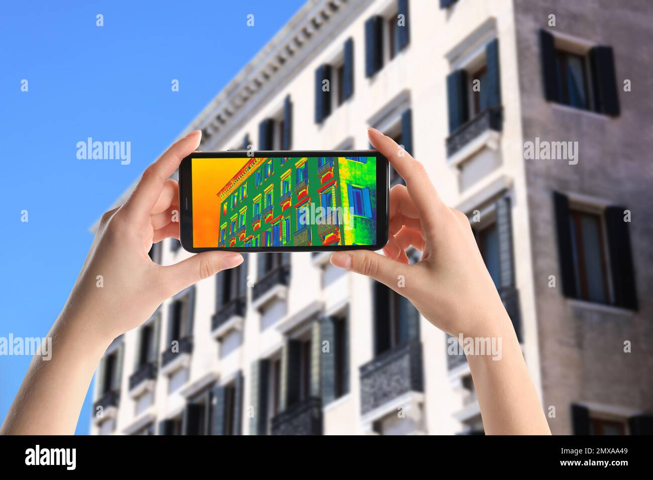 Woman detecting heat loss in building using thermal viewer on ...