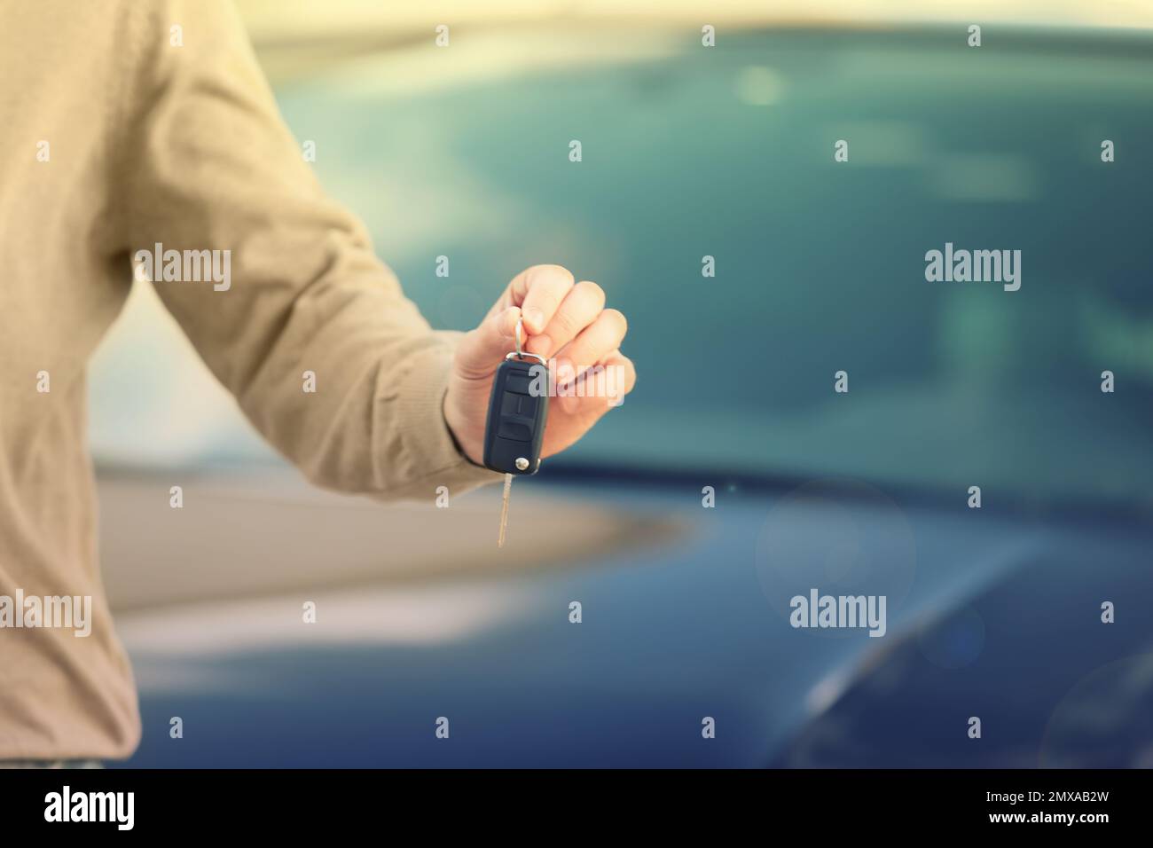 Man holding key in modern auto dealership, closeup. Buying new car ...