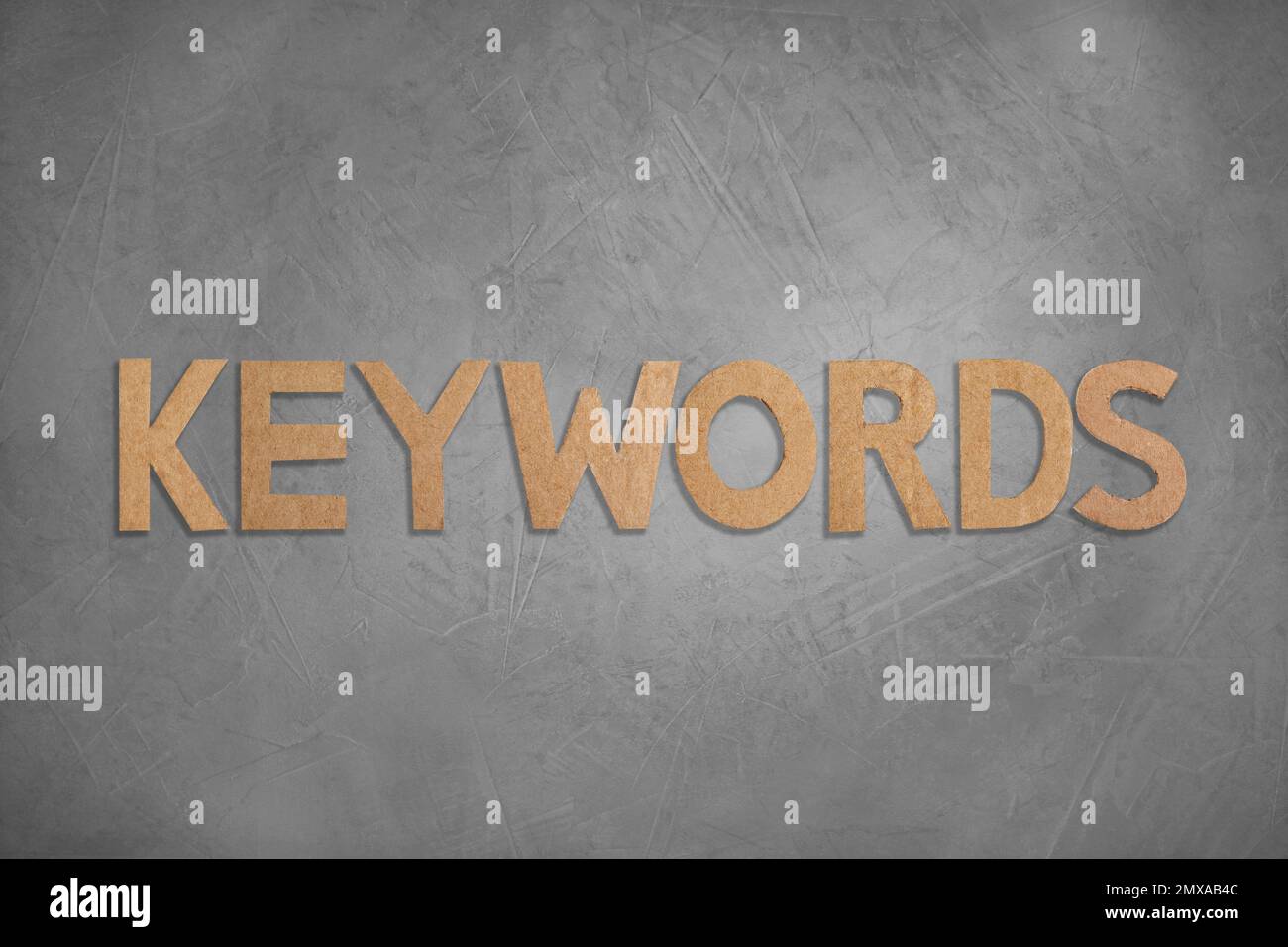 Text KEYWORDS made of cardboard on grey concrete surface, top view ...