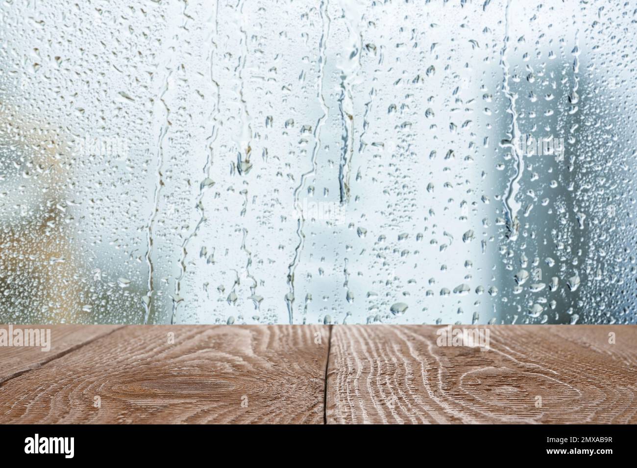 Wooden table near window on rainy day Stock Photo - Alamy