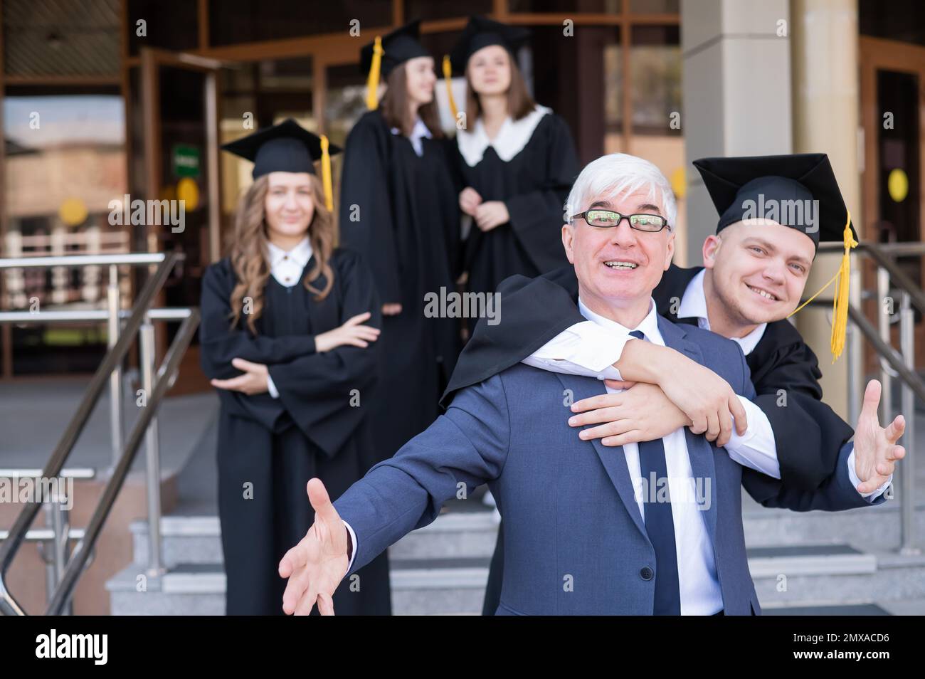Father and son embrace at graduation. Parent congratulates university ...